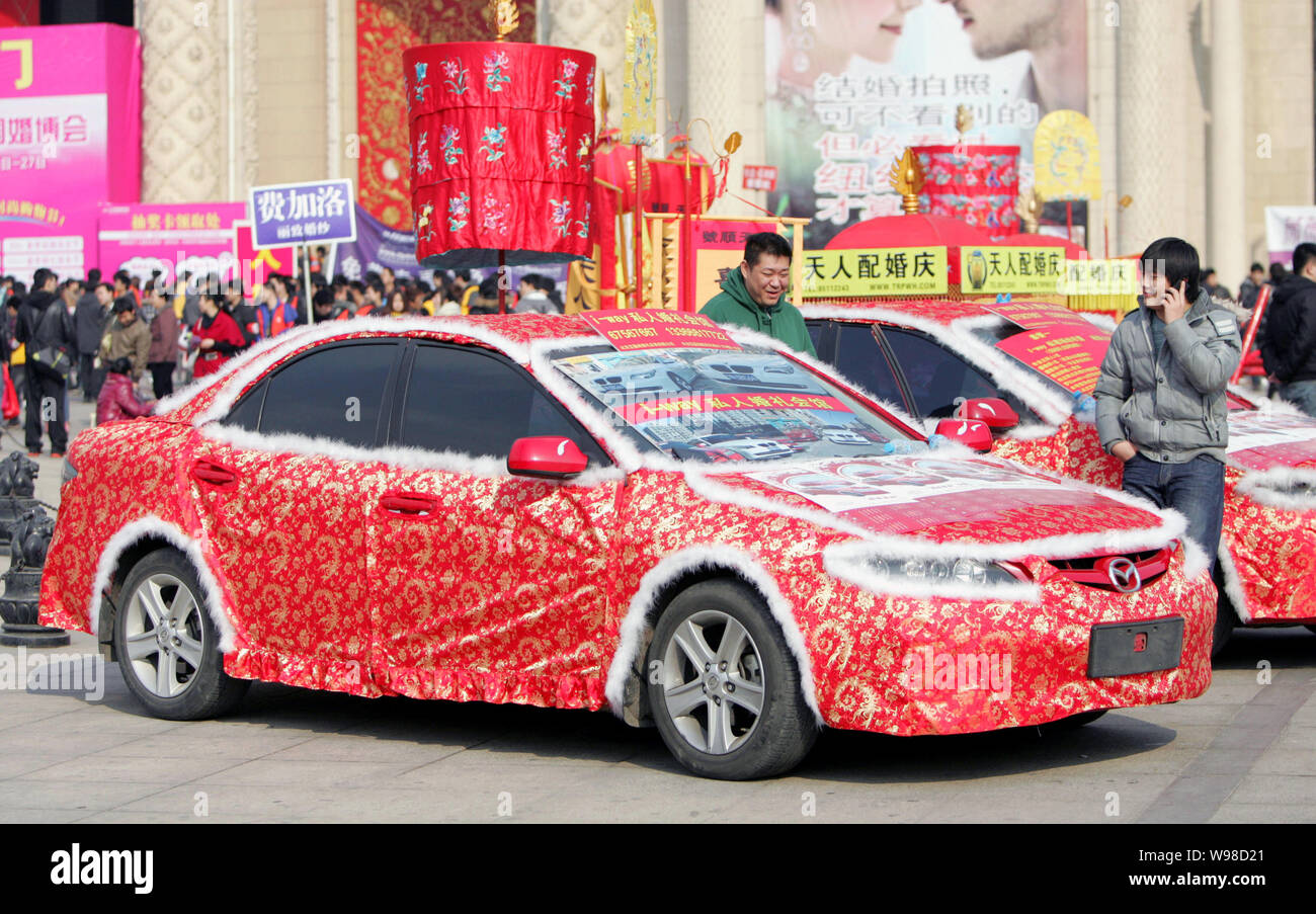 Visitors look at wedding cars dressed in materials traditionally used ...
