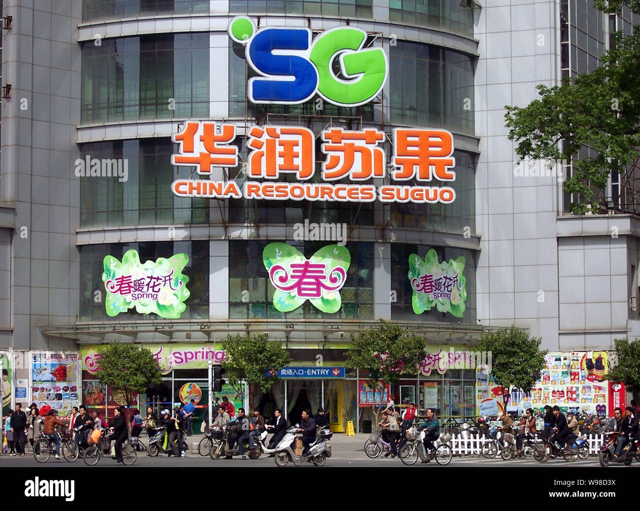 --FILE--Chinese cyclists pass by a China Resources Suguo supermarket in ...