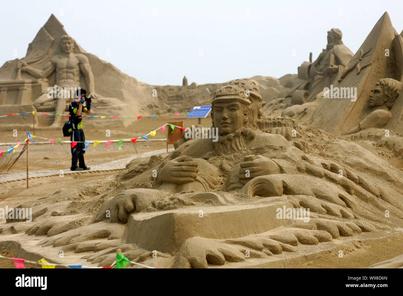 A tourist takes photos of sand sculptures at a sand sculpture park in ...