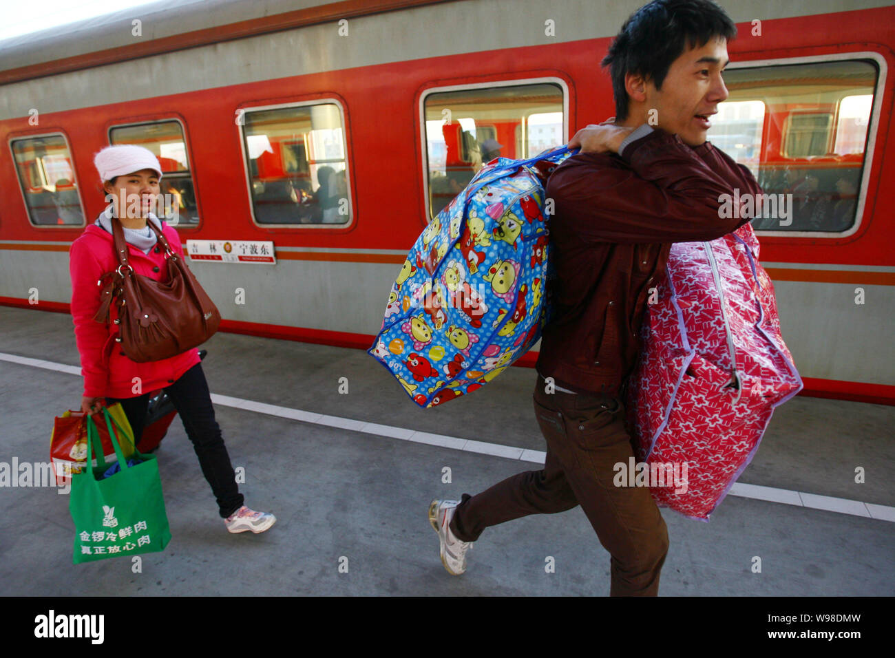 Chinese passengers carrying their luggages go to board their train at a ...
