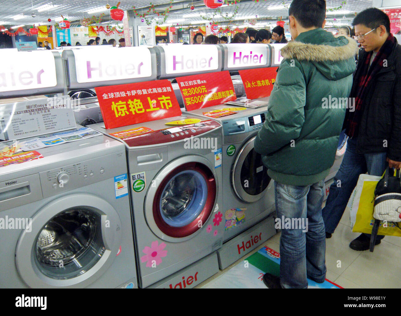 --FILE--Chinese customers shop for Haier cylinder washing machines at a ...