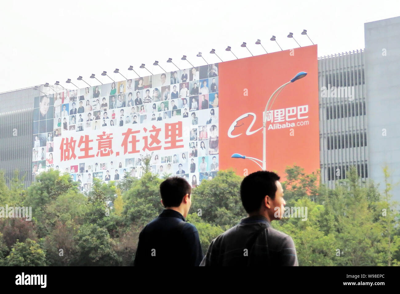 --FILE--Chinese men walk past a huge billboard of Alibaba at the ...