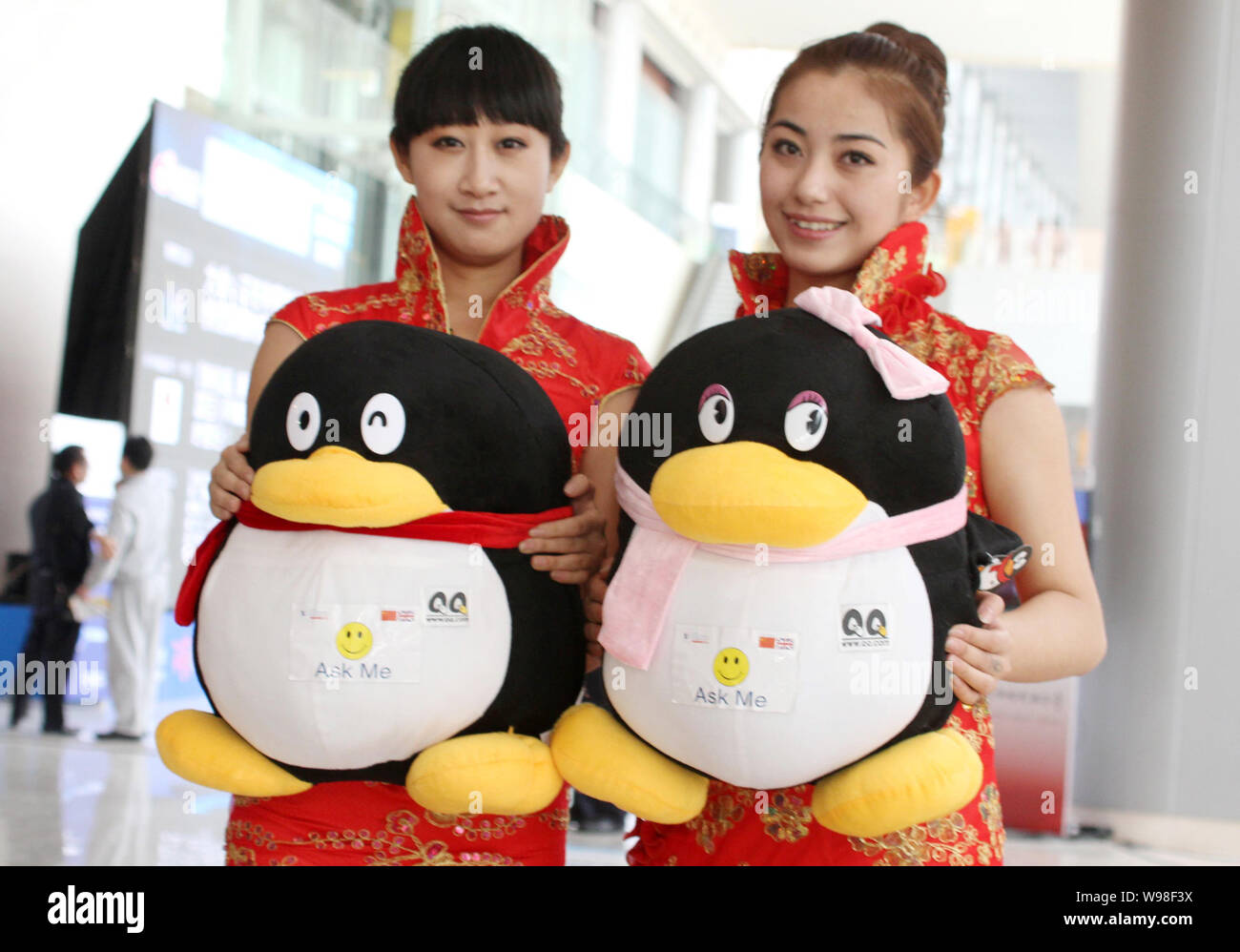 --FILE--Two girls hold toy penguins, the mascot of QQ.com of Tencent ...