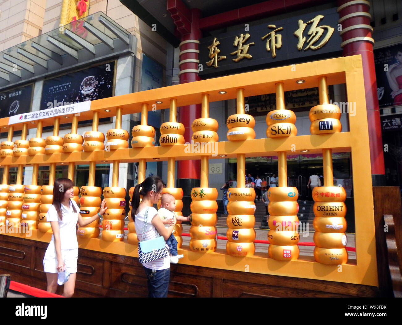 Visitors touches the counters on a huge golden abacus at the Wangfujing ...