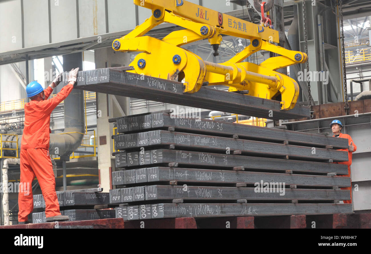 --FILE--Chinese factory workers hoist steel products at a steel plant ...