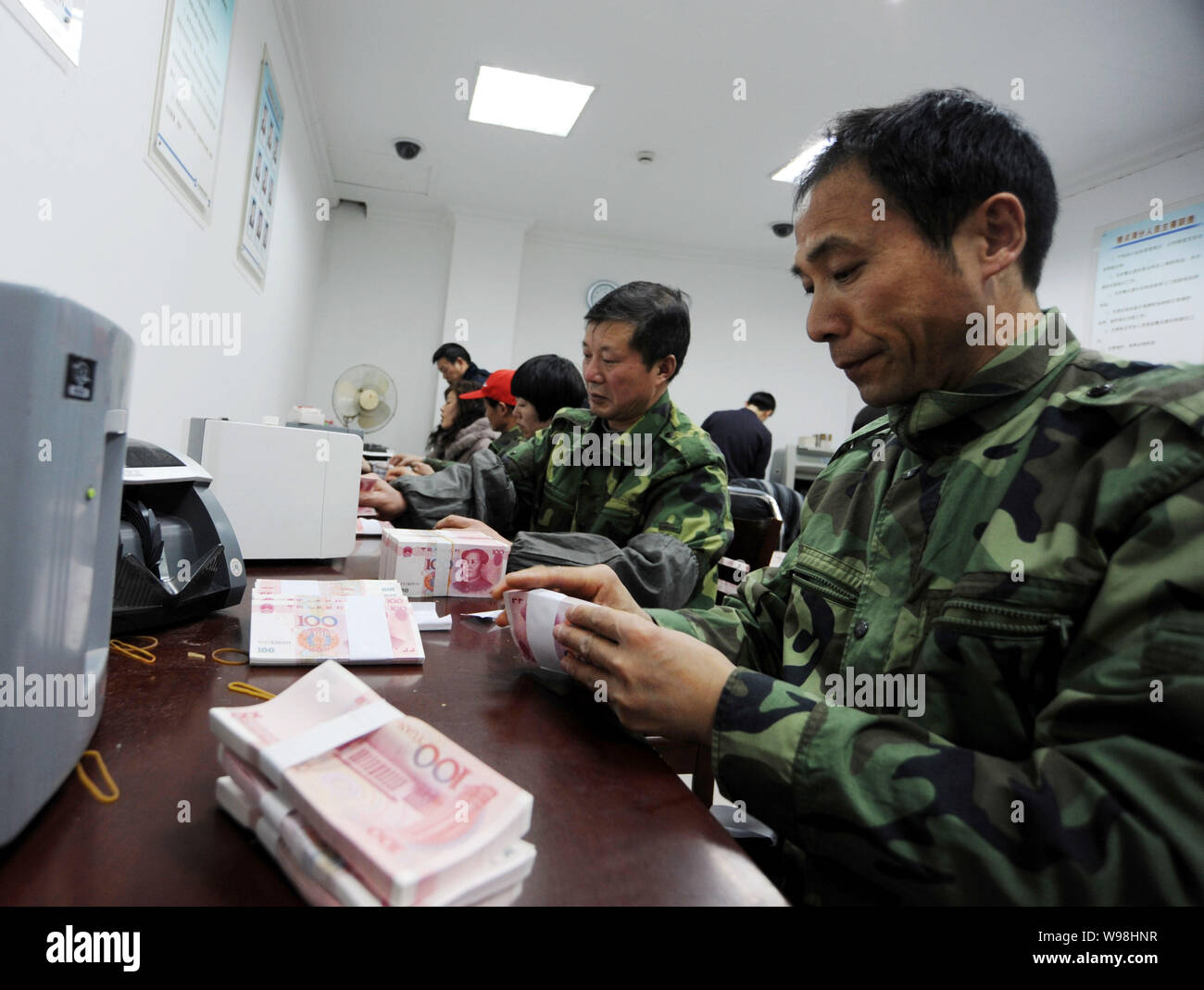 Chinese clerks count RMB (renminbi) yuan banknotes at a bank in Haian ...