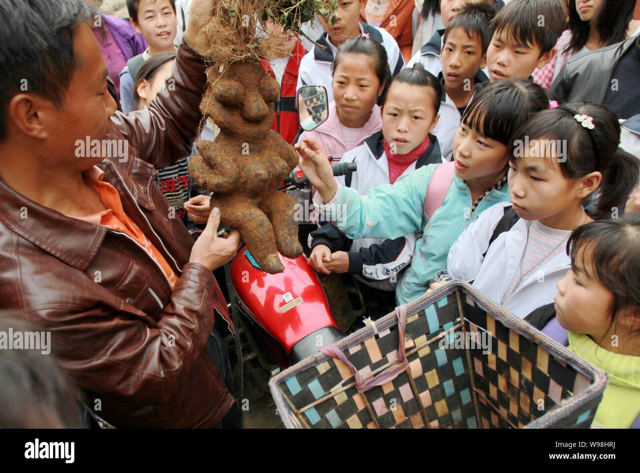 Chinese famer Wang Dewen shows students a human shaped fleece flower ...