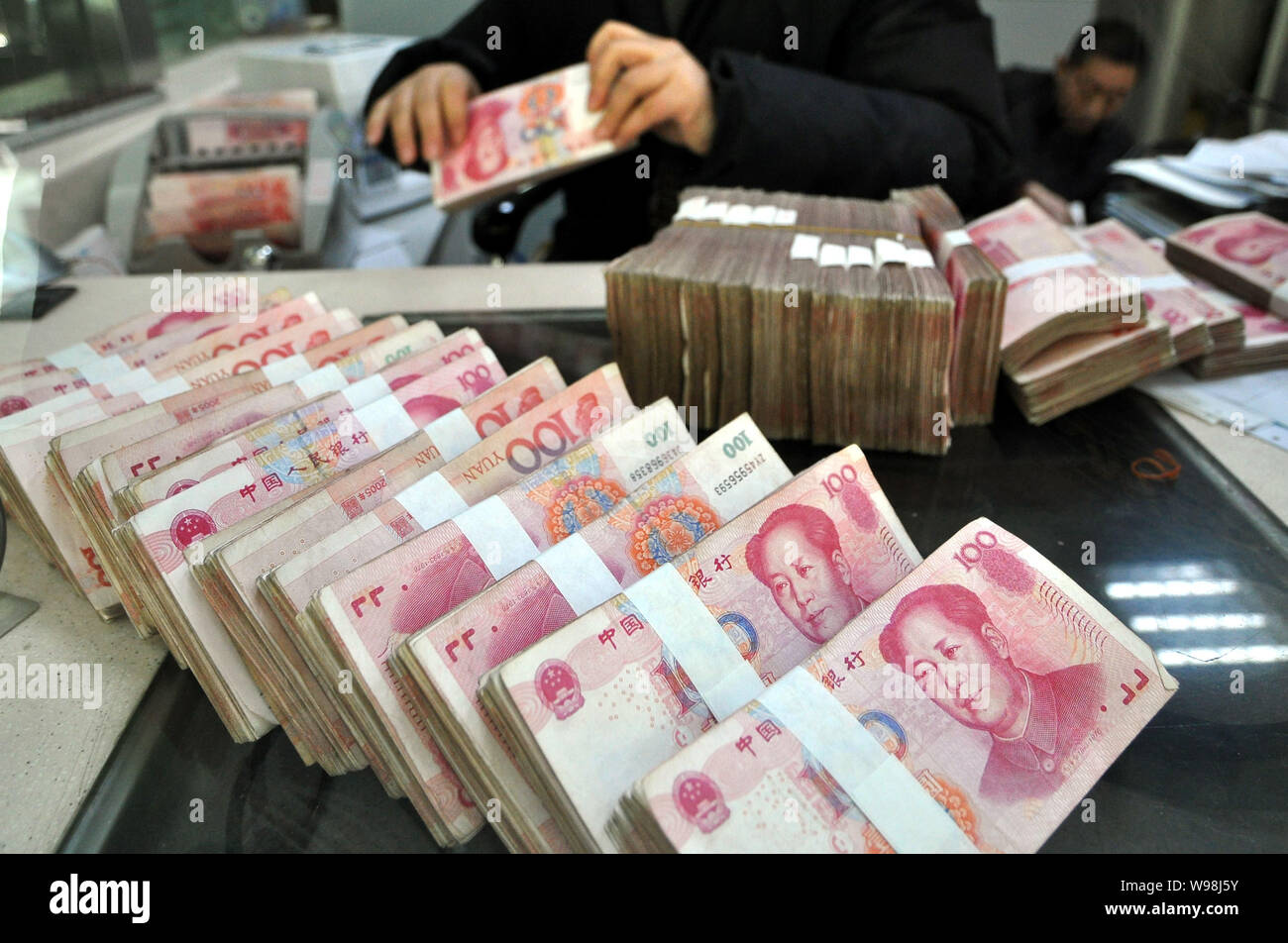 A Chinese clerk counts RMB (renminbi) yuan banknotes at a bank in ...