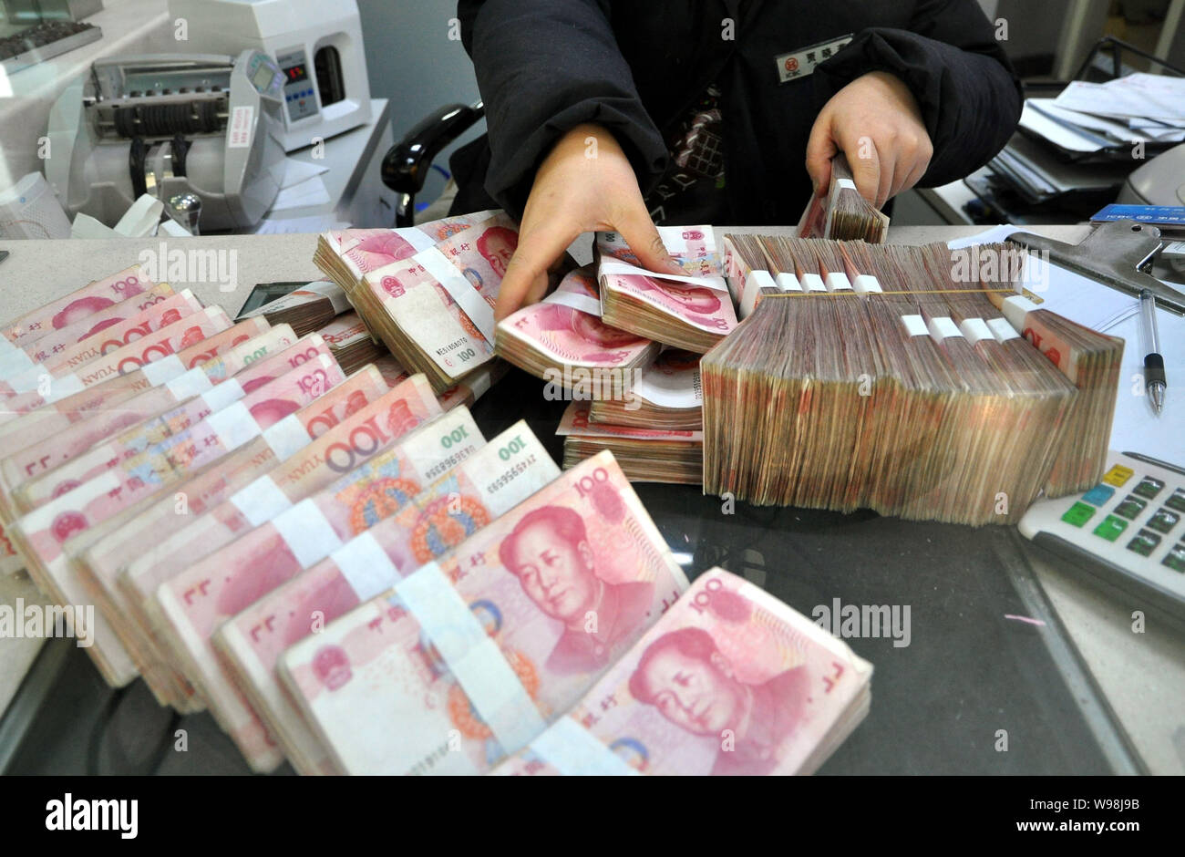 A Chinese clerk counts RMB (renminbi) yuan banknotes at a bank in ...