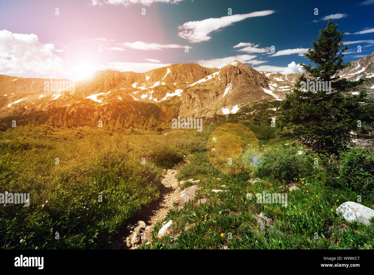 Sunset light shining behind a distant mountain range and a dirt hiking ...