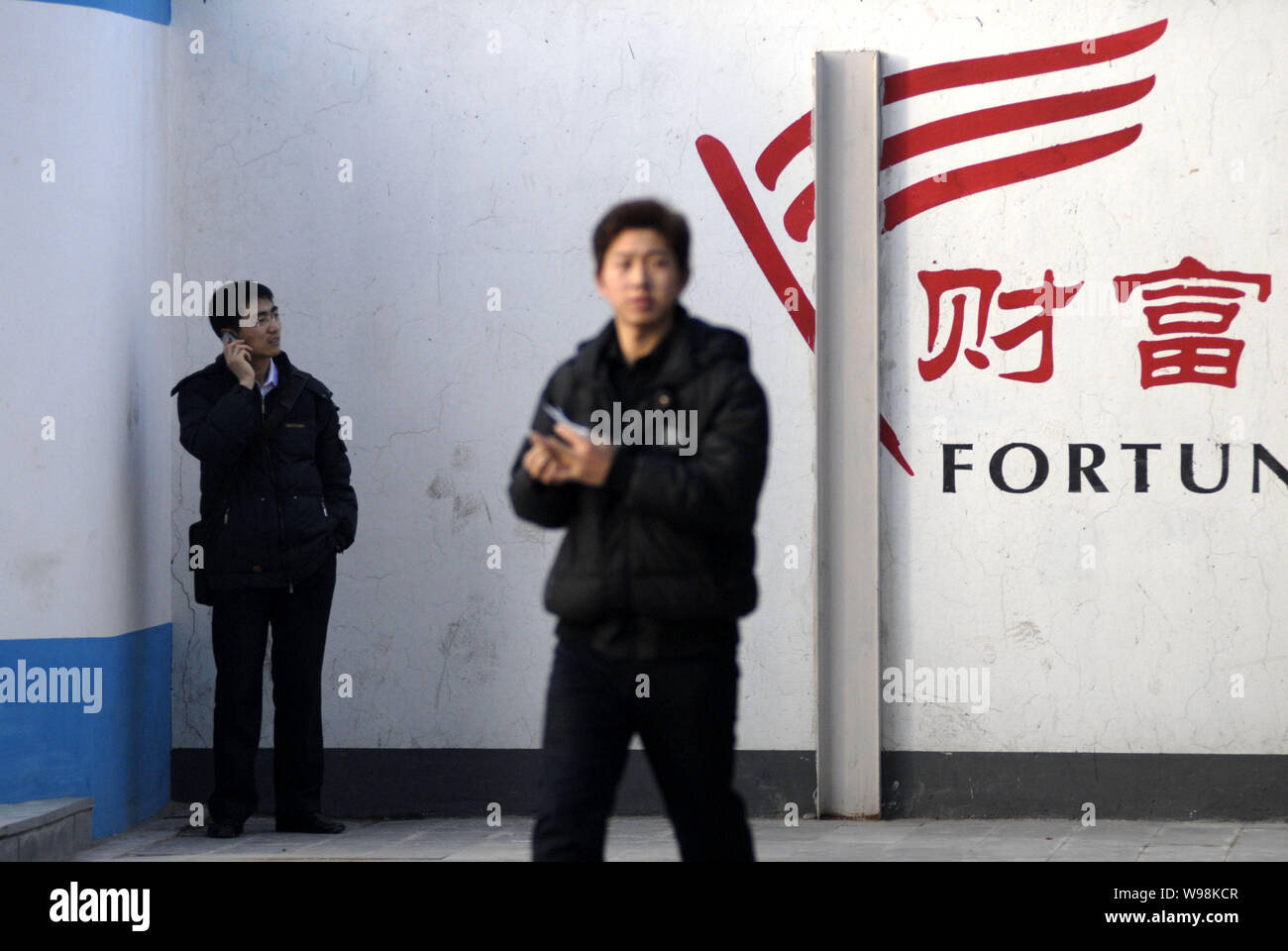 --FILE--A Chinese man uses his mobile phone next to a sign meaning ...