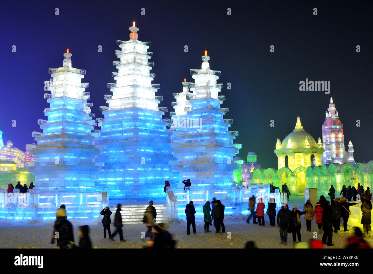 Visitors look at illuminated ice-made structures during the 27th Harbin ...