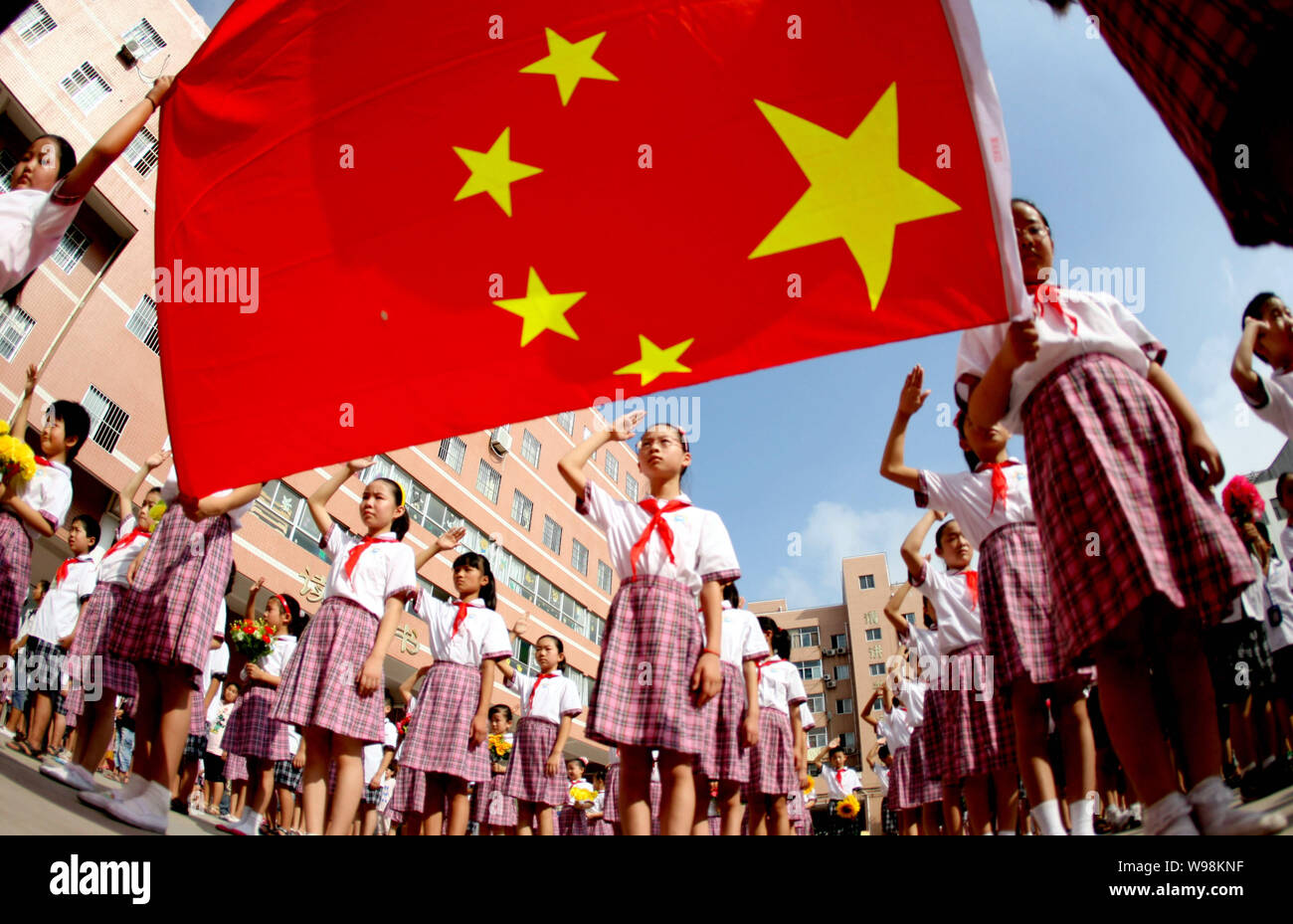 Chinese pupils display a Chinese national flag and salute during a flag ...