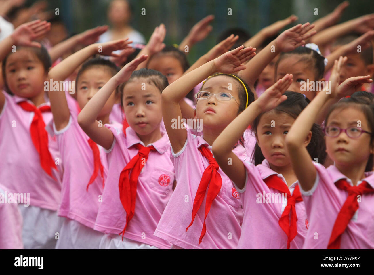 Chinese pupils salute during a flag-raising ceremony on the first day ...