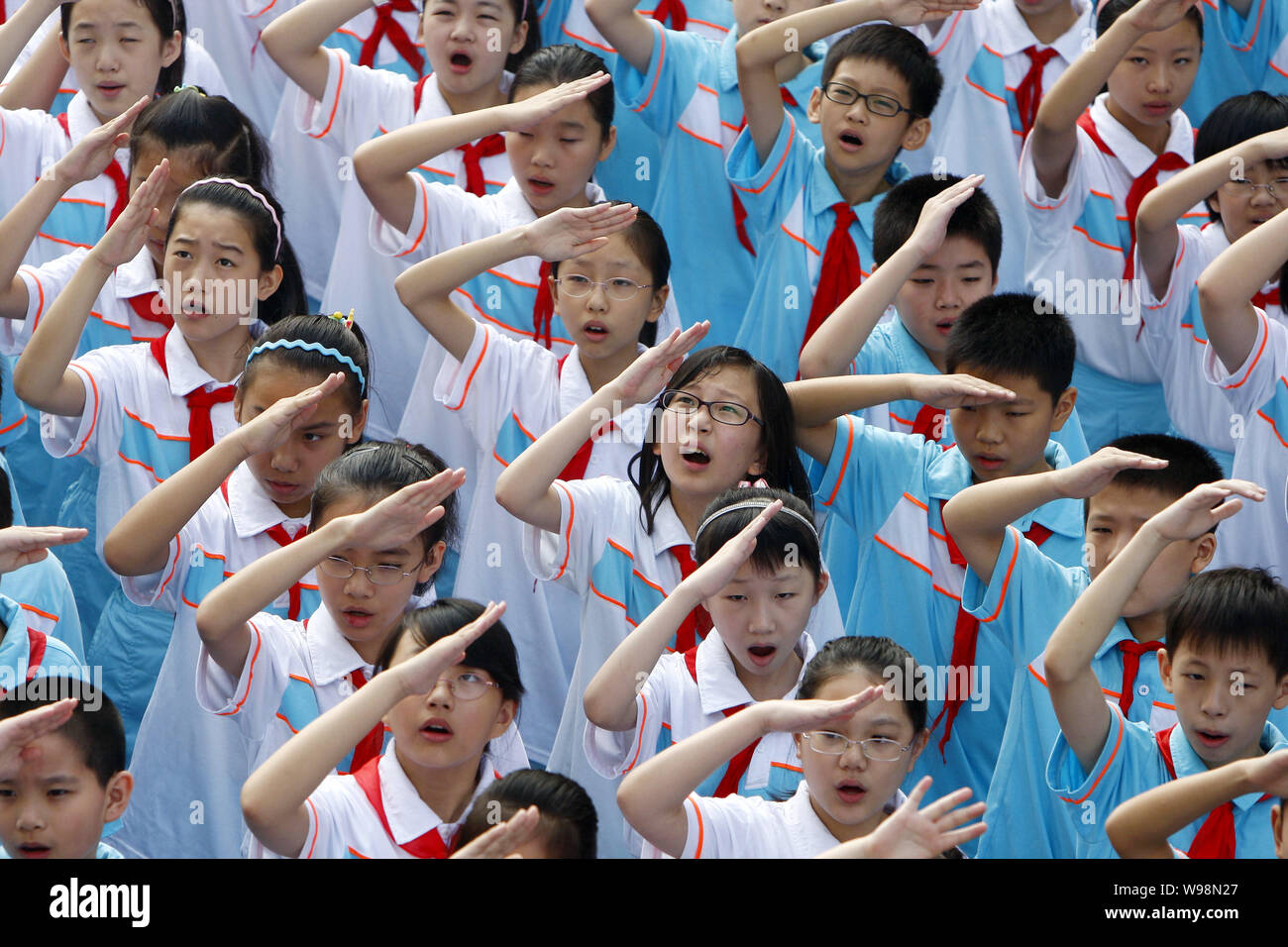 Chinese students salute during a flag-raising ceremony on the first day ...
