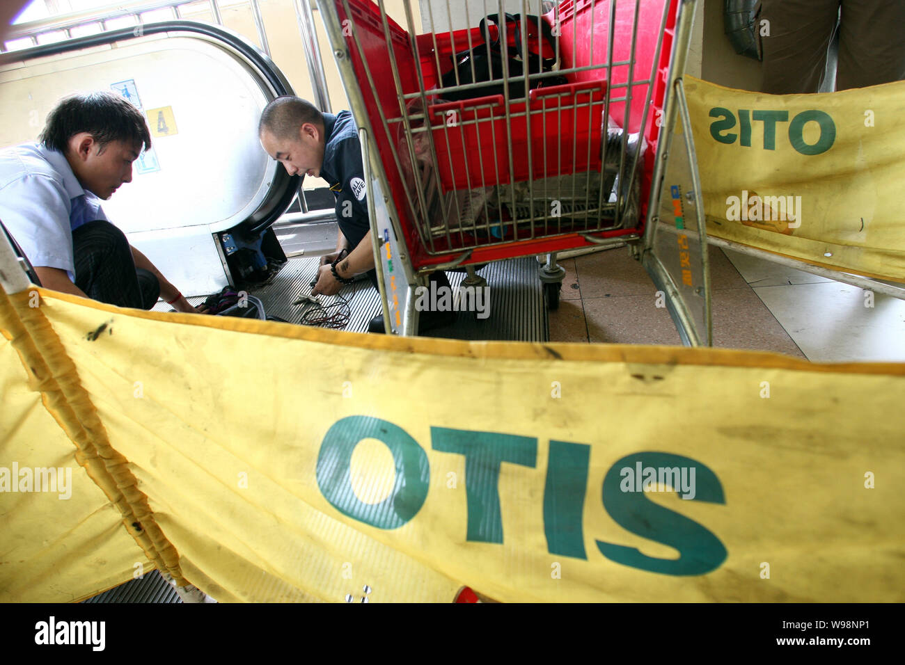 Workers check and repair an OTIS escalator at a subway station in ...