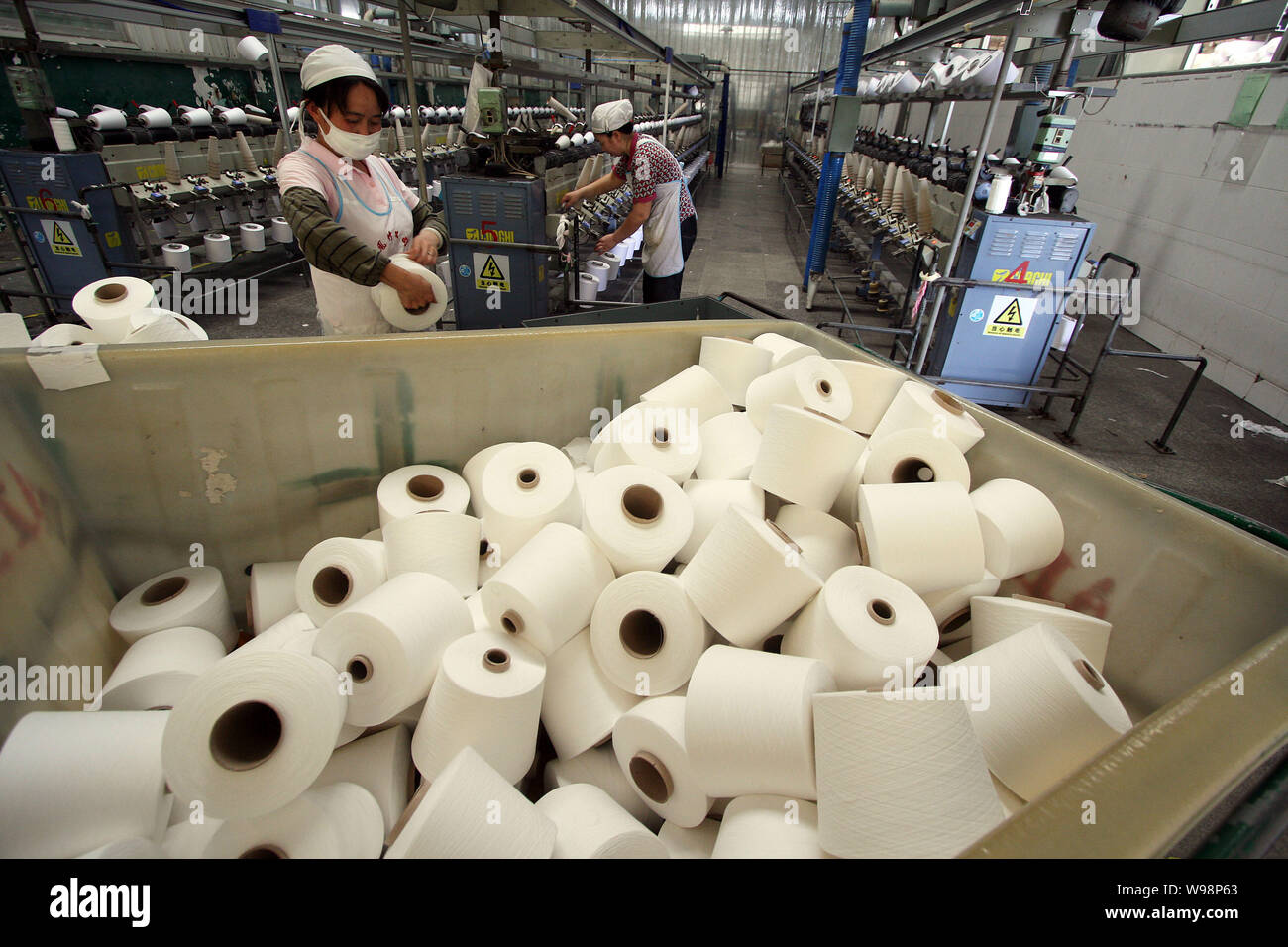 --FILE--Two female Chinese workers handle the production of yarn on a spinning machine at a ...