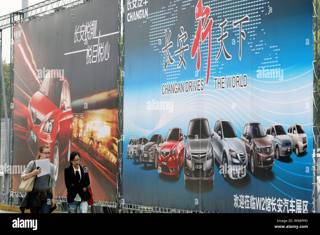 Visitors walk past advertisements for ChangAn cars in the preparation ...