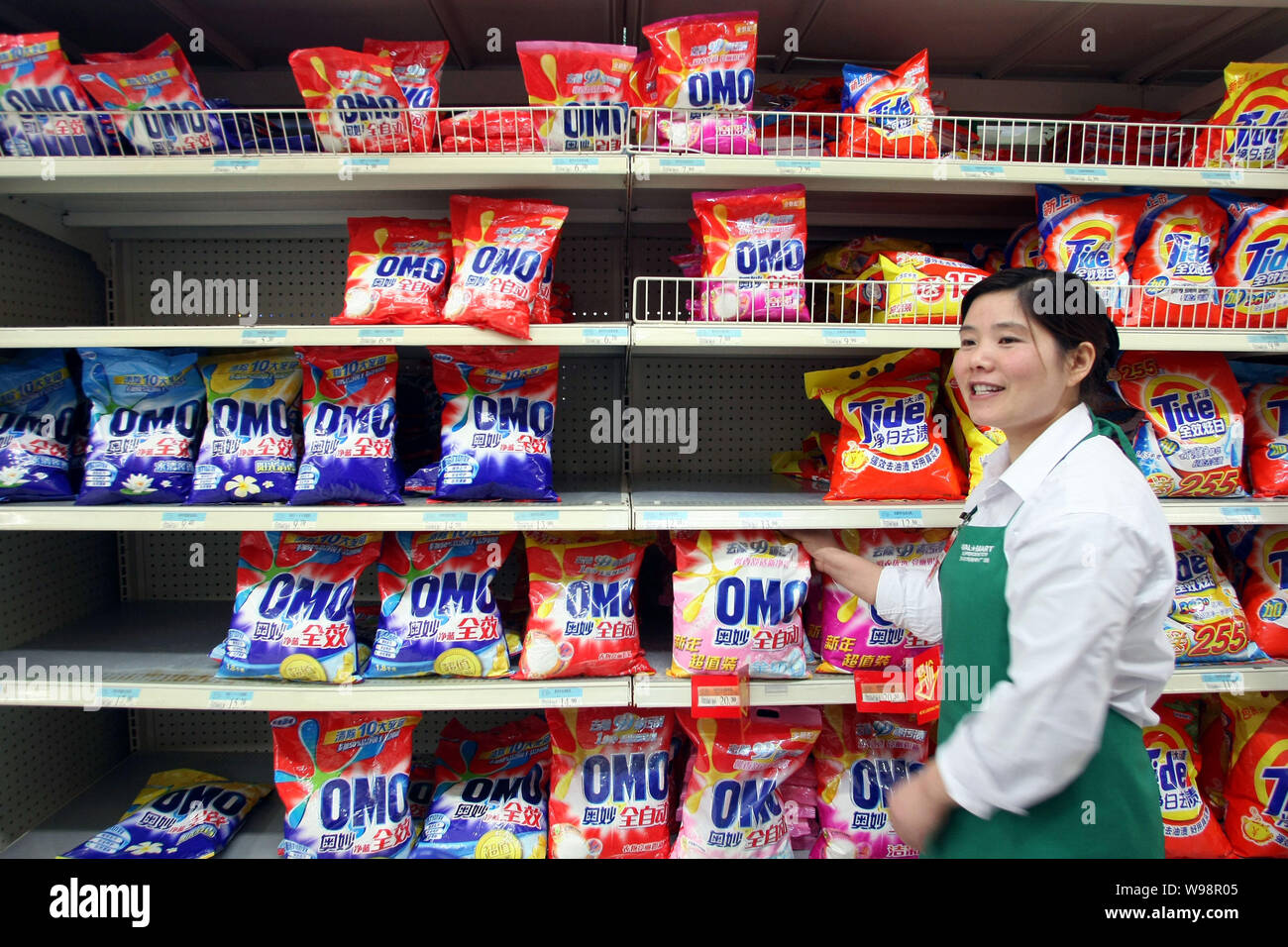 A Chinese staff walks past a half-empty shelf of washing powder at a ...