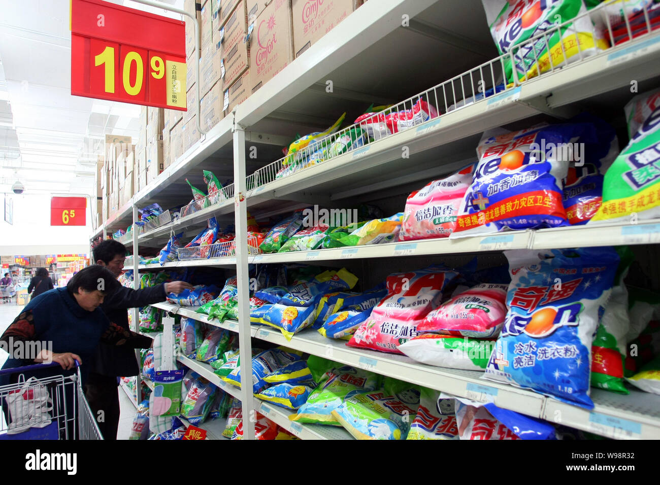 Chinese shoppers buy washing powder in front of a half-empty shelf at a ...