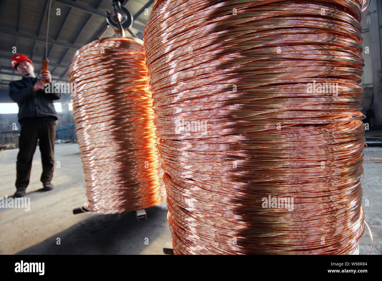 A Chinese worker moves coils of copper tubes at a copper products plant ...