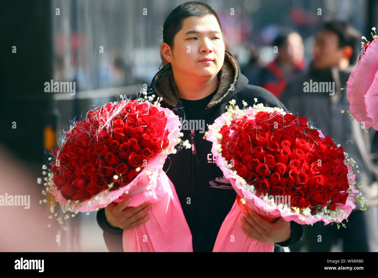 A Chinese man holds bouquets of roses for Valentines Day on the street ...