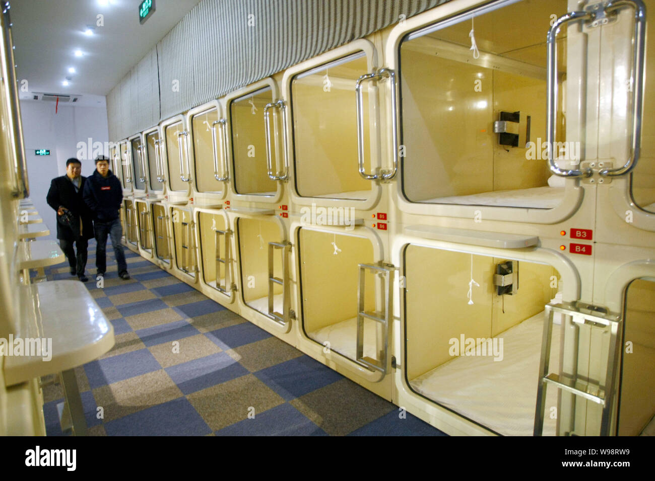 Chinese men walk past cabinet-sized rooms at Chinas first capsule hotel ...