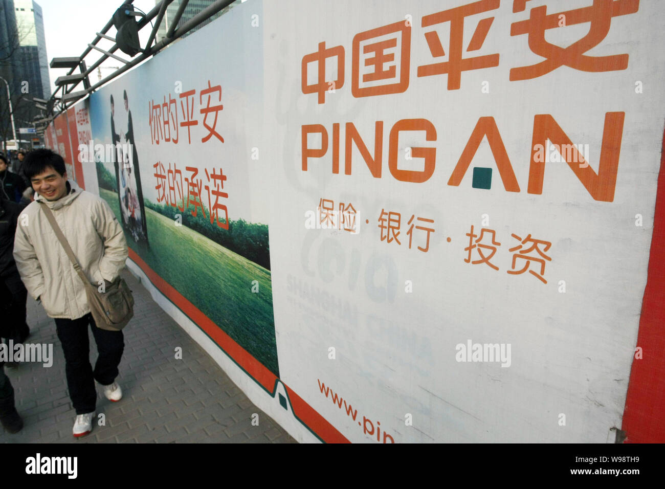 --FILE--Local Chinese residents walk past an advertisement for Ping An ...