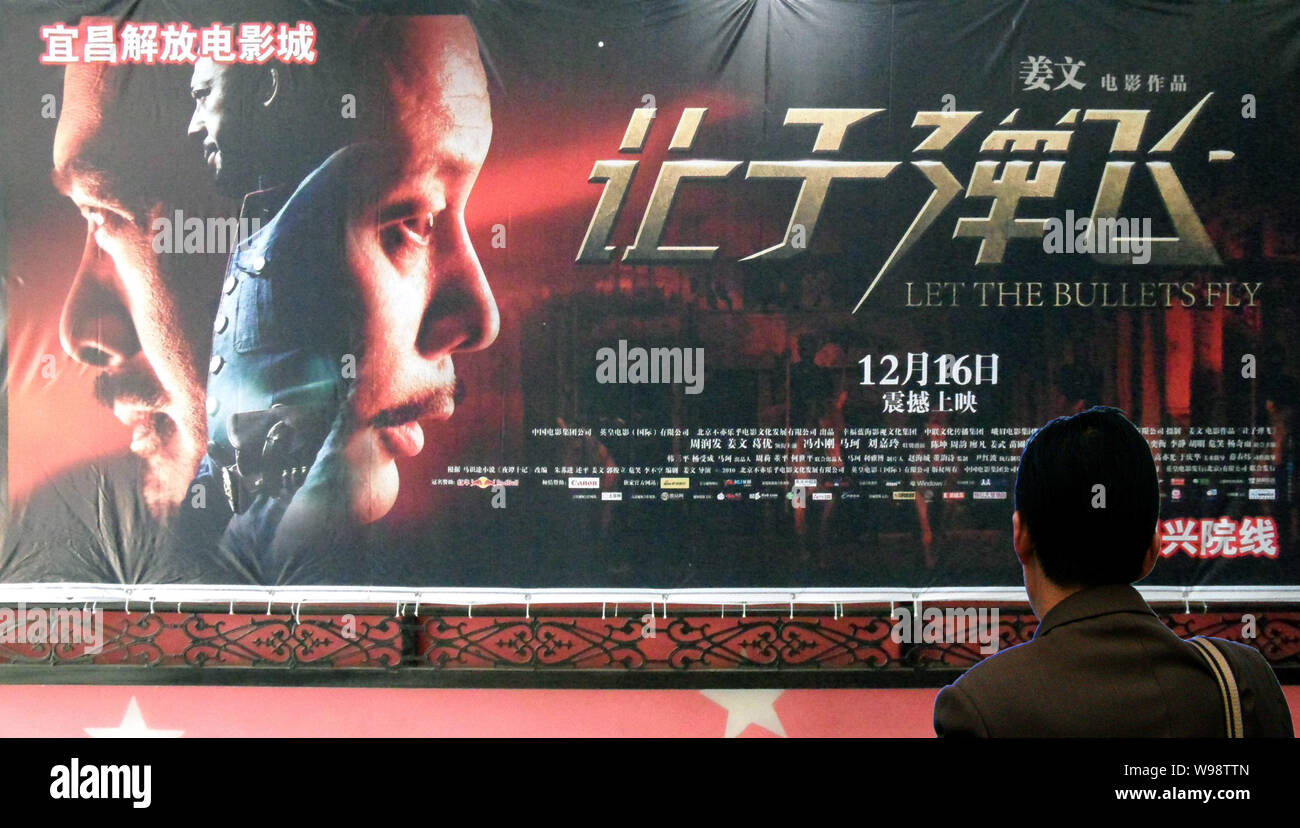 A Chinese man looks at a poster of the film, Let The Bullets Fly, at a ...