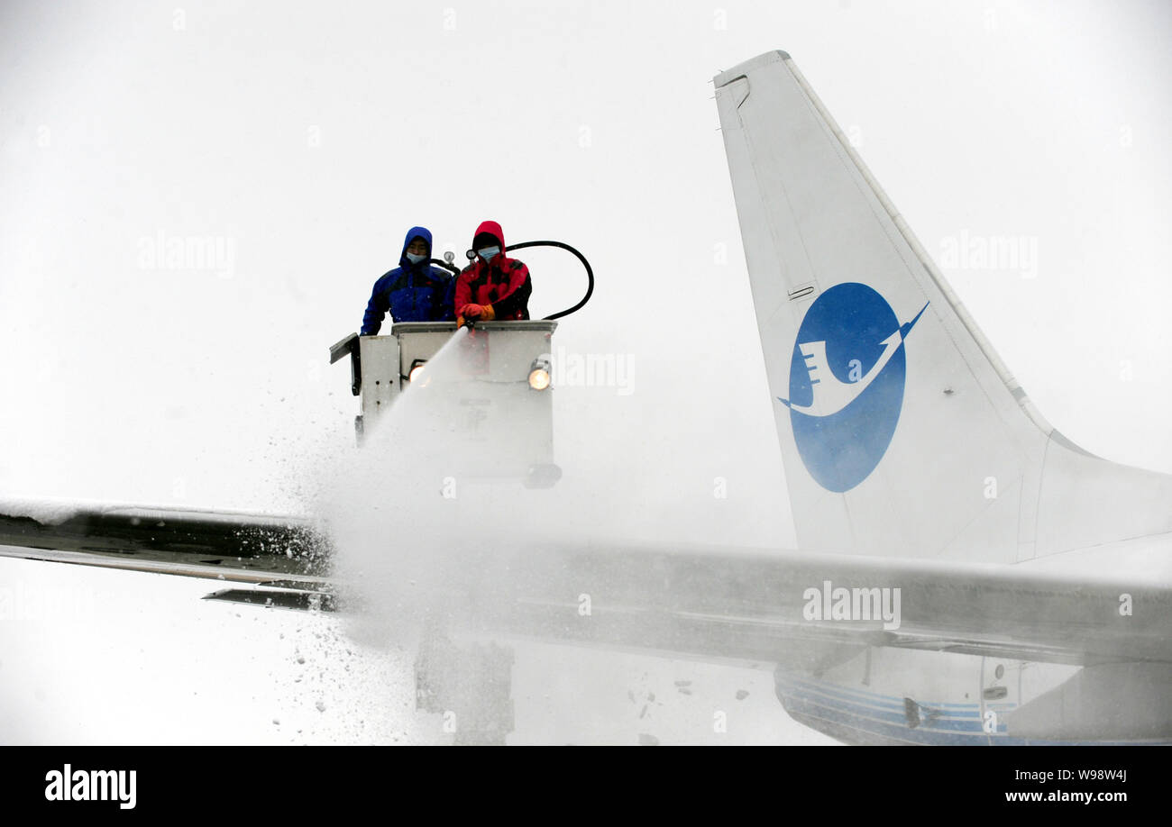 Chinese ground crew members deice a plane of Xiamen Airlines in the ...