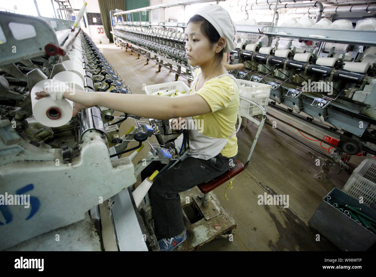 A female Chinese worker handles the production of yarn to be exported ...