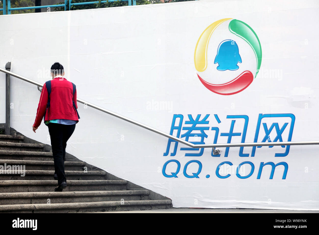 --File-- A Chinese woman walks past an advertisement of QQ.com in ...