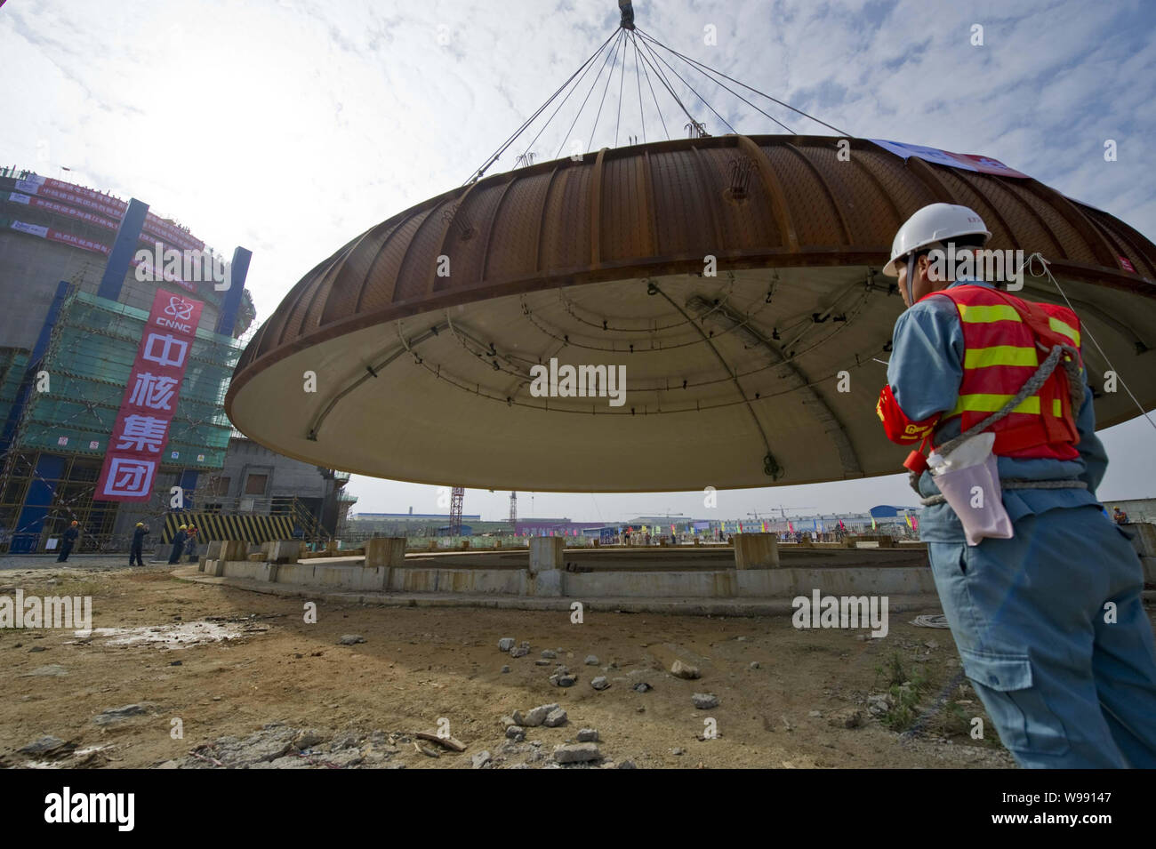 Workers watch the dome of the containment structure for the No.1 ...