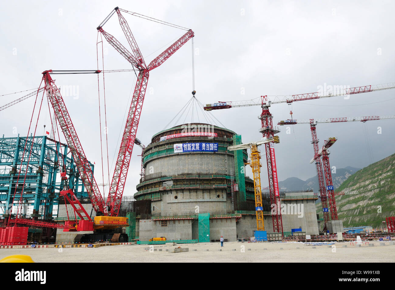 The dome of a containment structure is being hoisted onto the structure ...