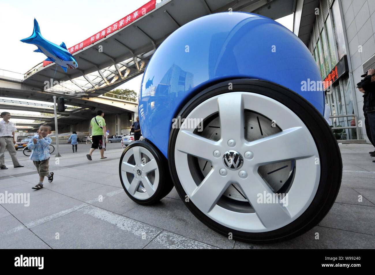 Local residents walk past a concept car of Volkswagens Peoples Car ...