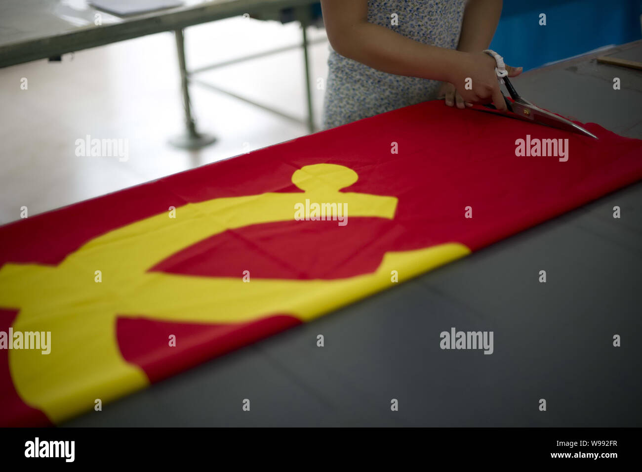 A worker scissors a flag of the Communist Party of China (CPC) at ...