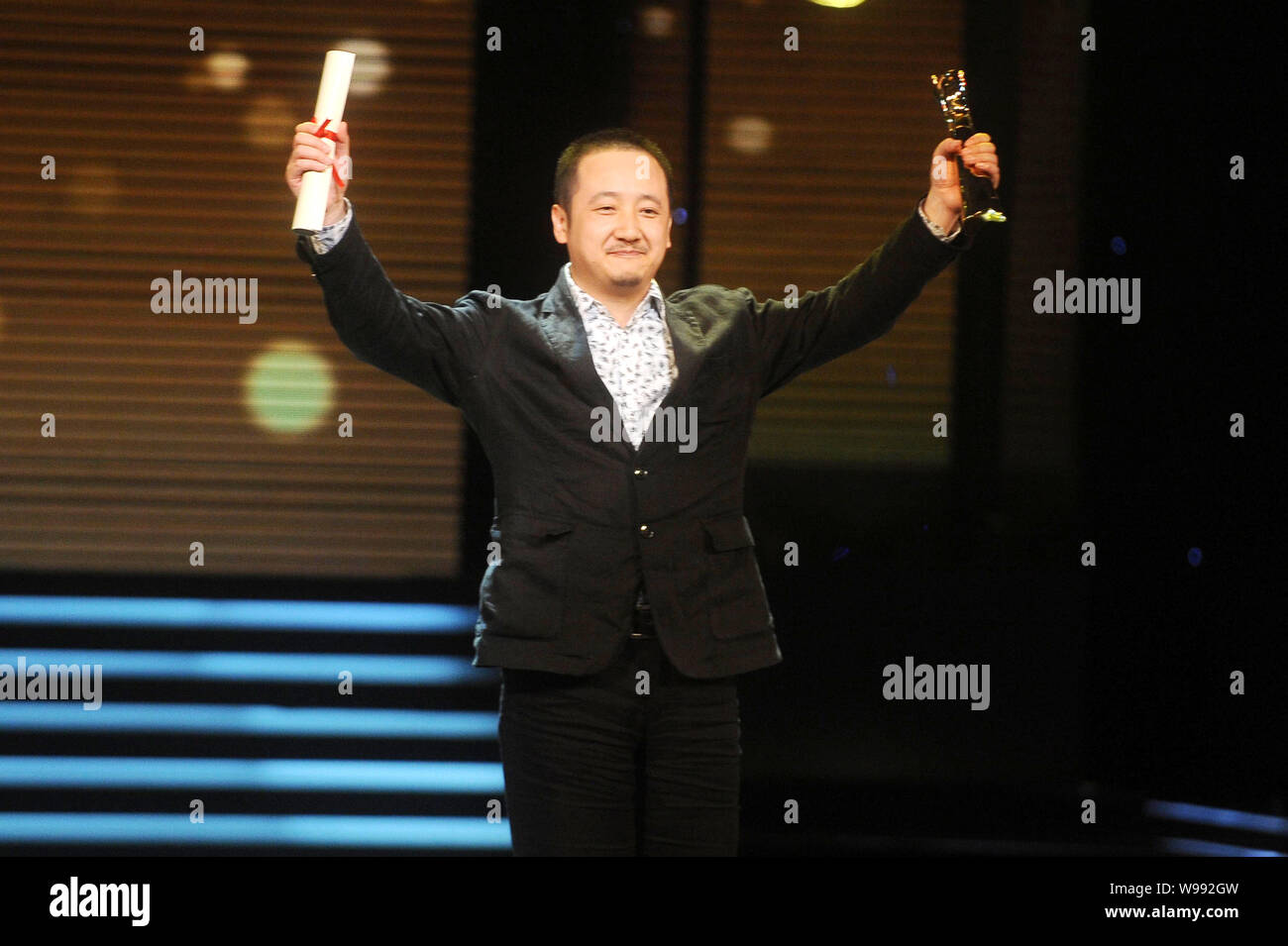 Chinese actor Han Jie holds up his trophy for the Best Director during ...