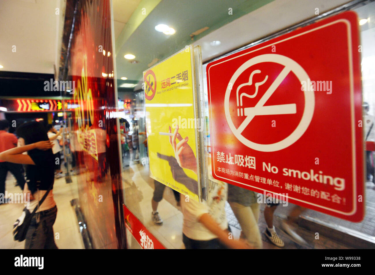 Shoppers walk past signs for No Smoking at a mall in Wuhan city ...