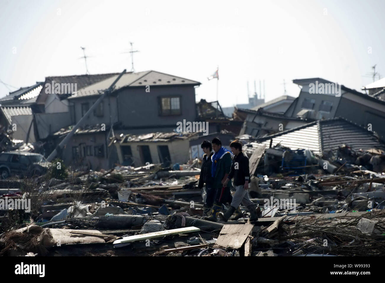 Local young Japanese men walk in the debris of the tsunami devastation ...