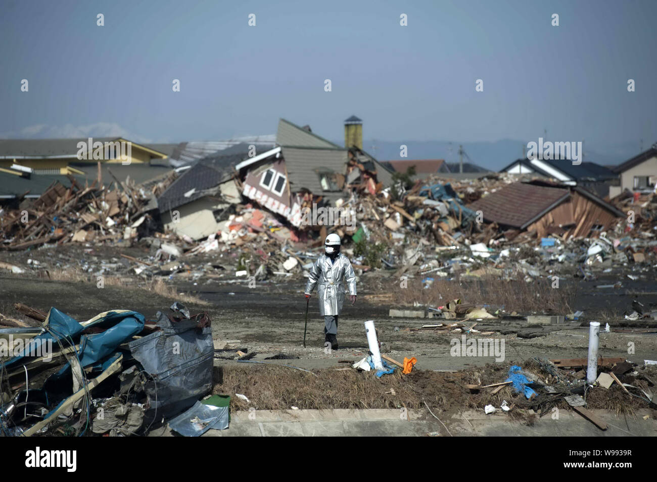 A Japanese rescuer walks past the debris of the tsunami devastation ...