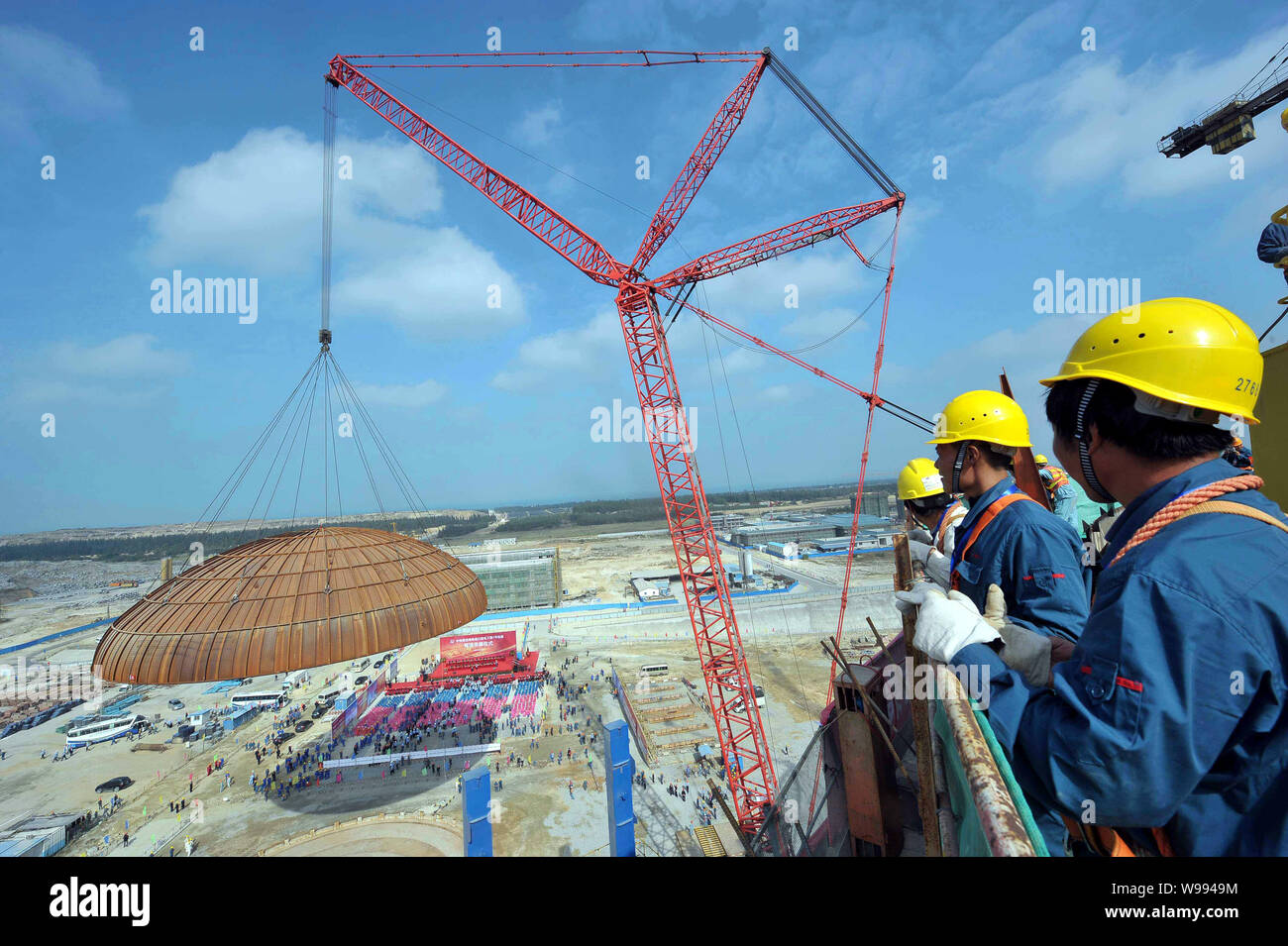 Workers watch the dome of the containment structure for the No.1 ...