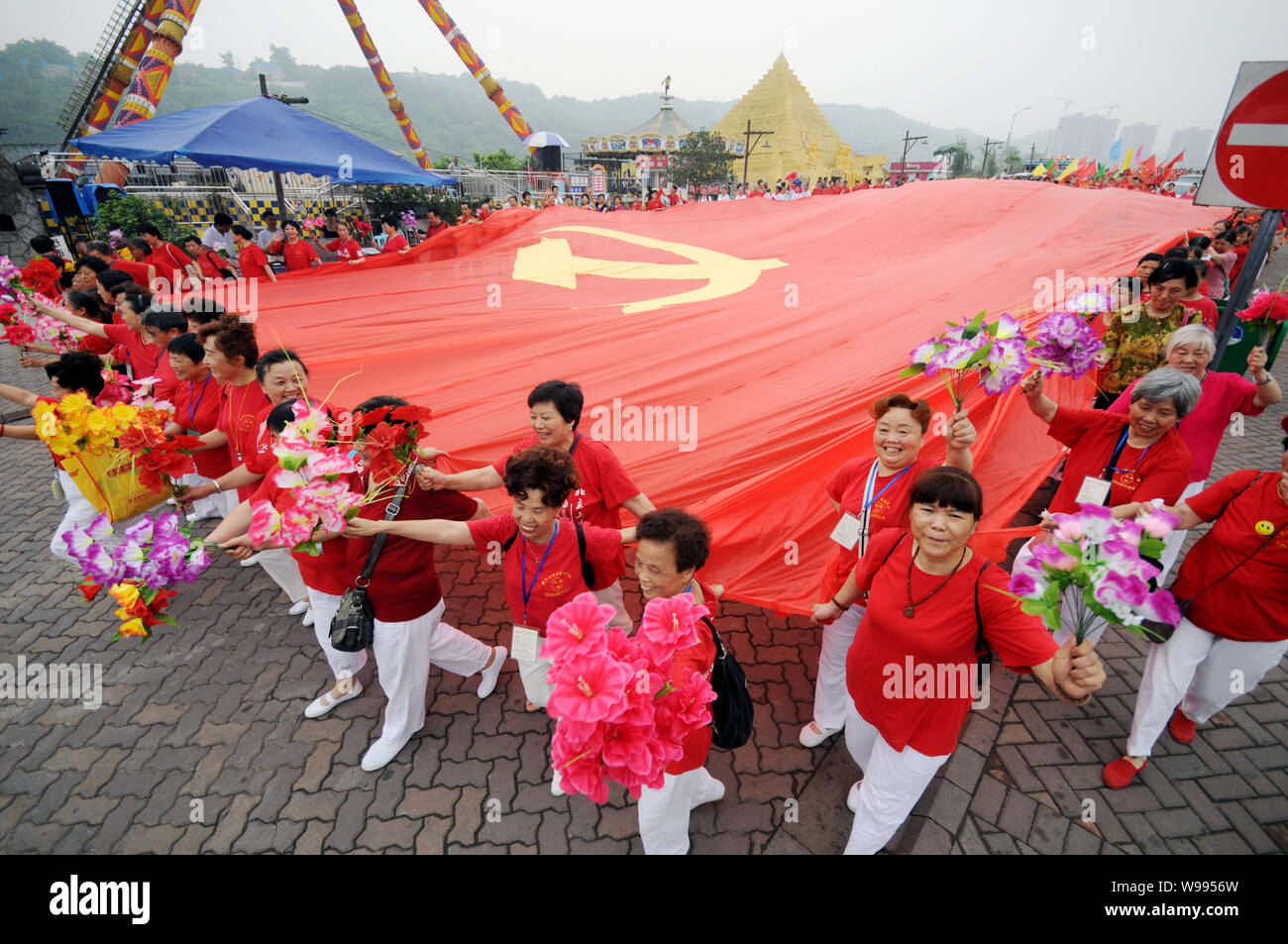 Local residents display a huge flag of the Communist Party of China ...