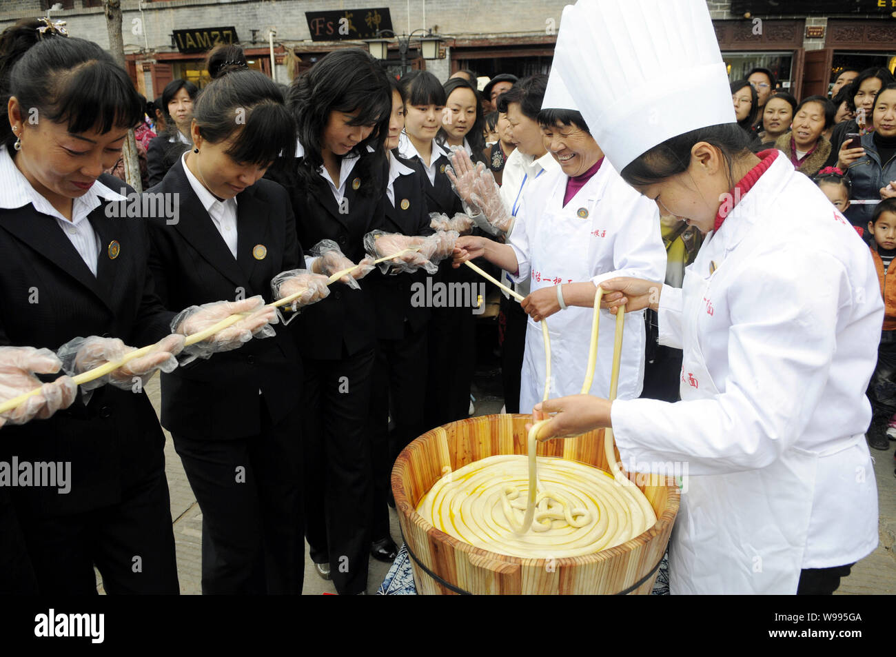 Cooks and other participants make a 1,704-meter-long stretch of noodle ...