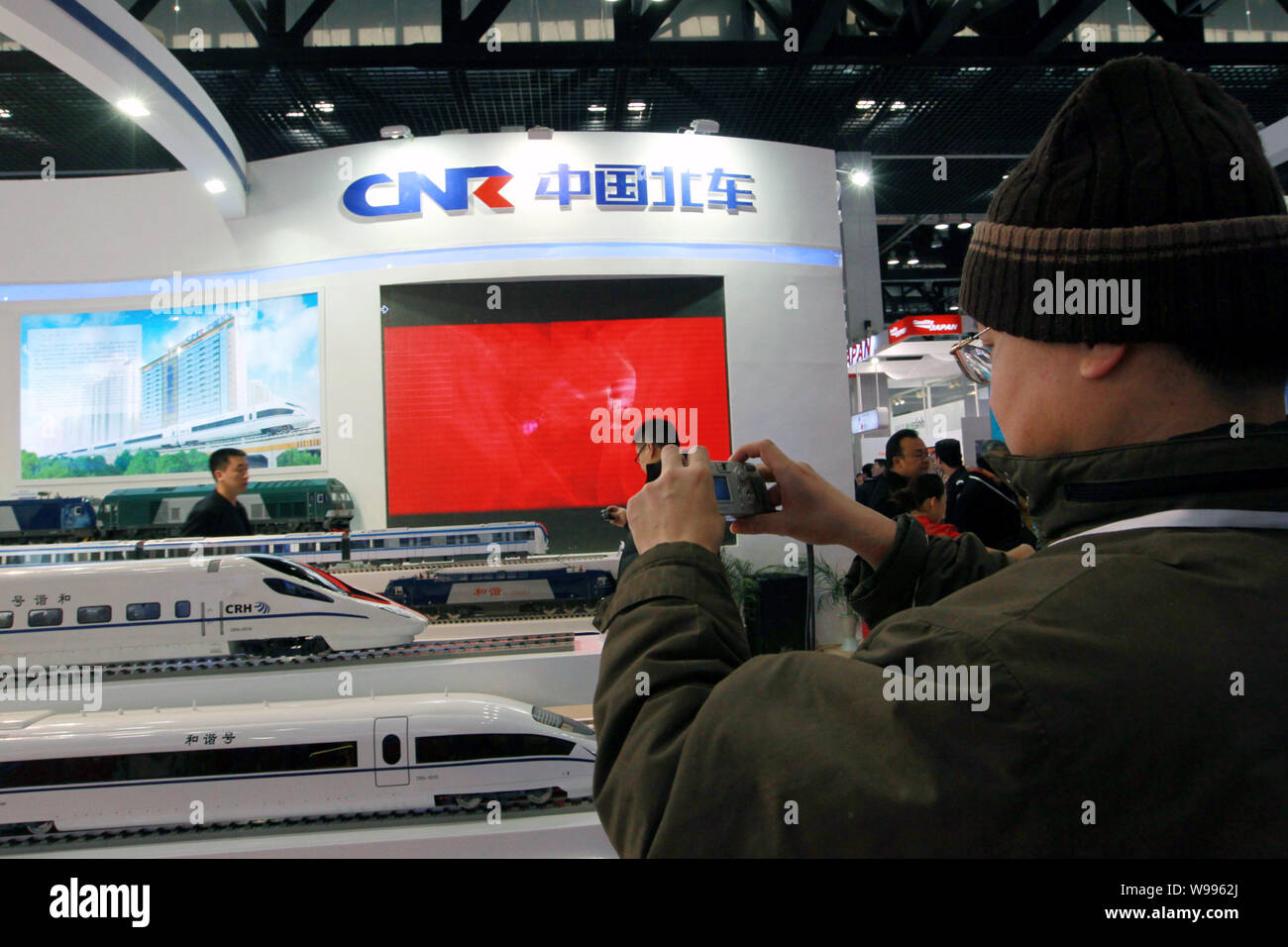 A visitor takes photos of models of CRH high-speed trains at the stand ...