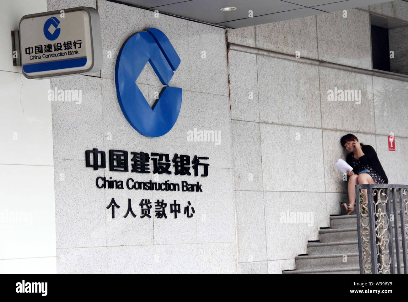 --File--A Chinese woman is seen next to a name board of a branch office ...
