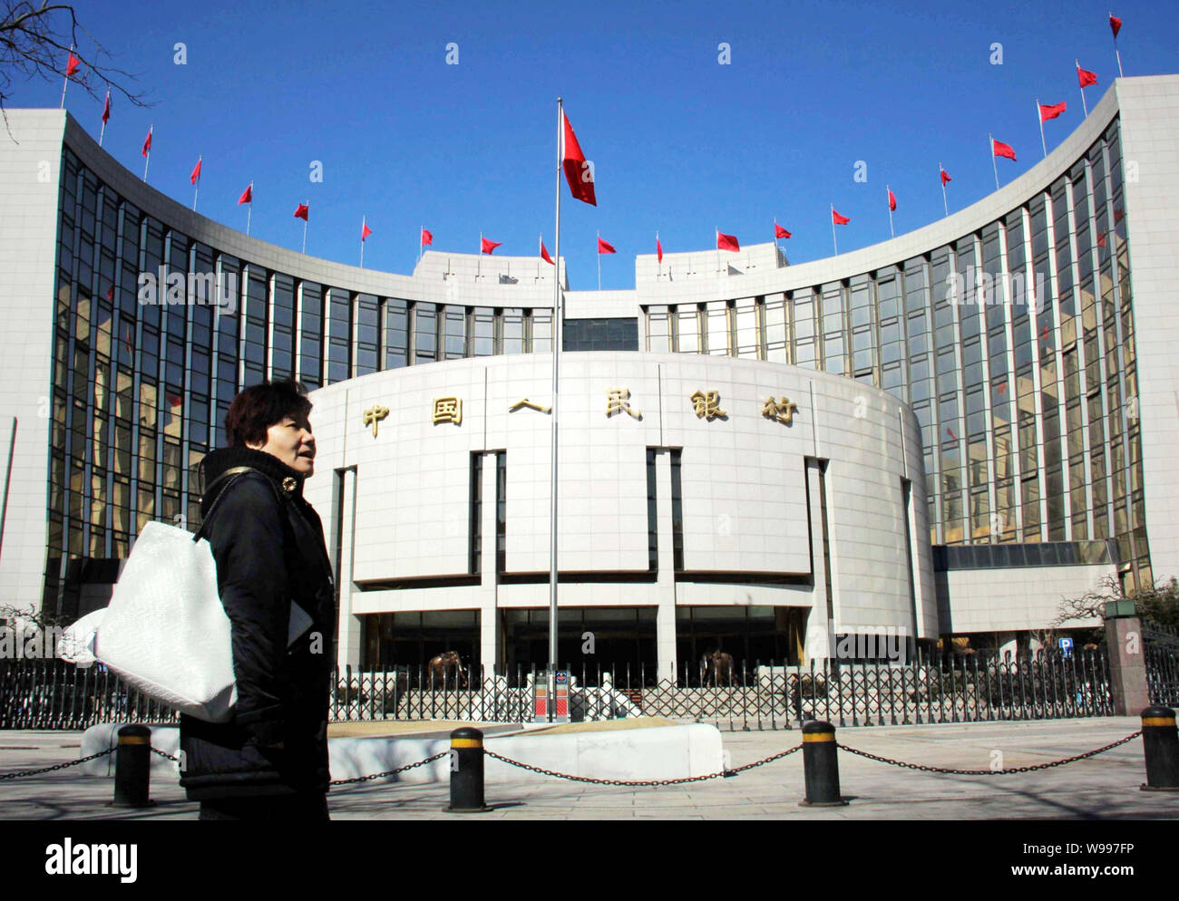 --FILE--A woman walks past the headquarters and head office of the ...