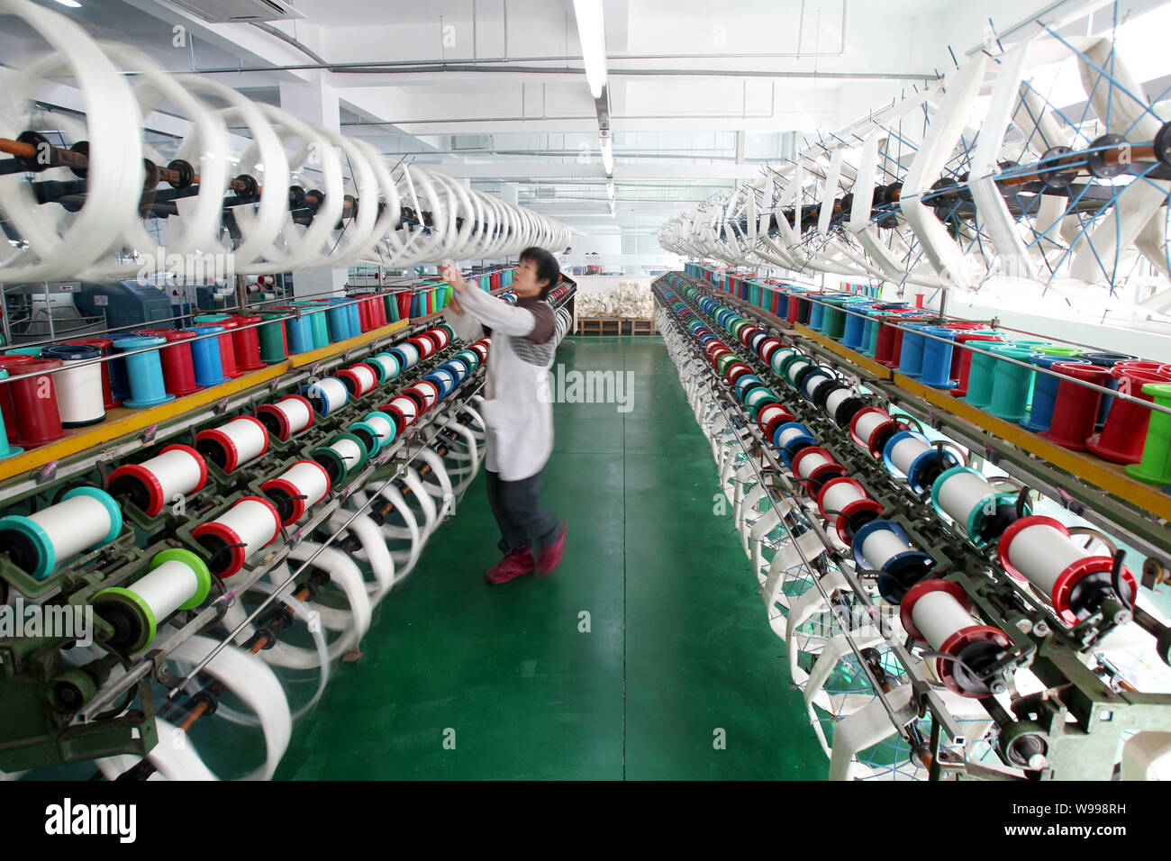 --FILE--A female Chinese worker checks yarn on the spinning machine at ...