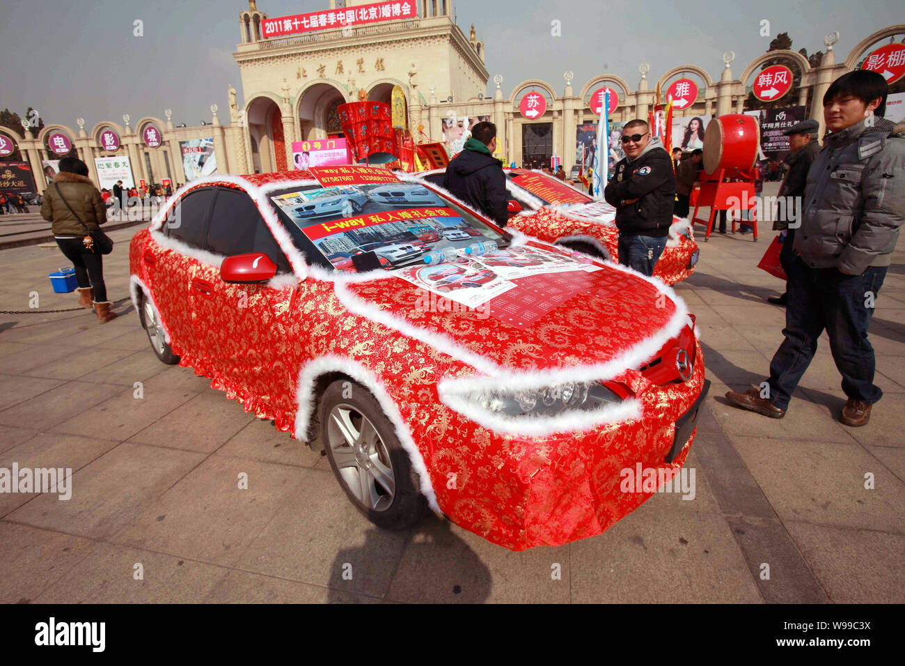 Visitors look at wedding cars dressed in materials traditionally used ...