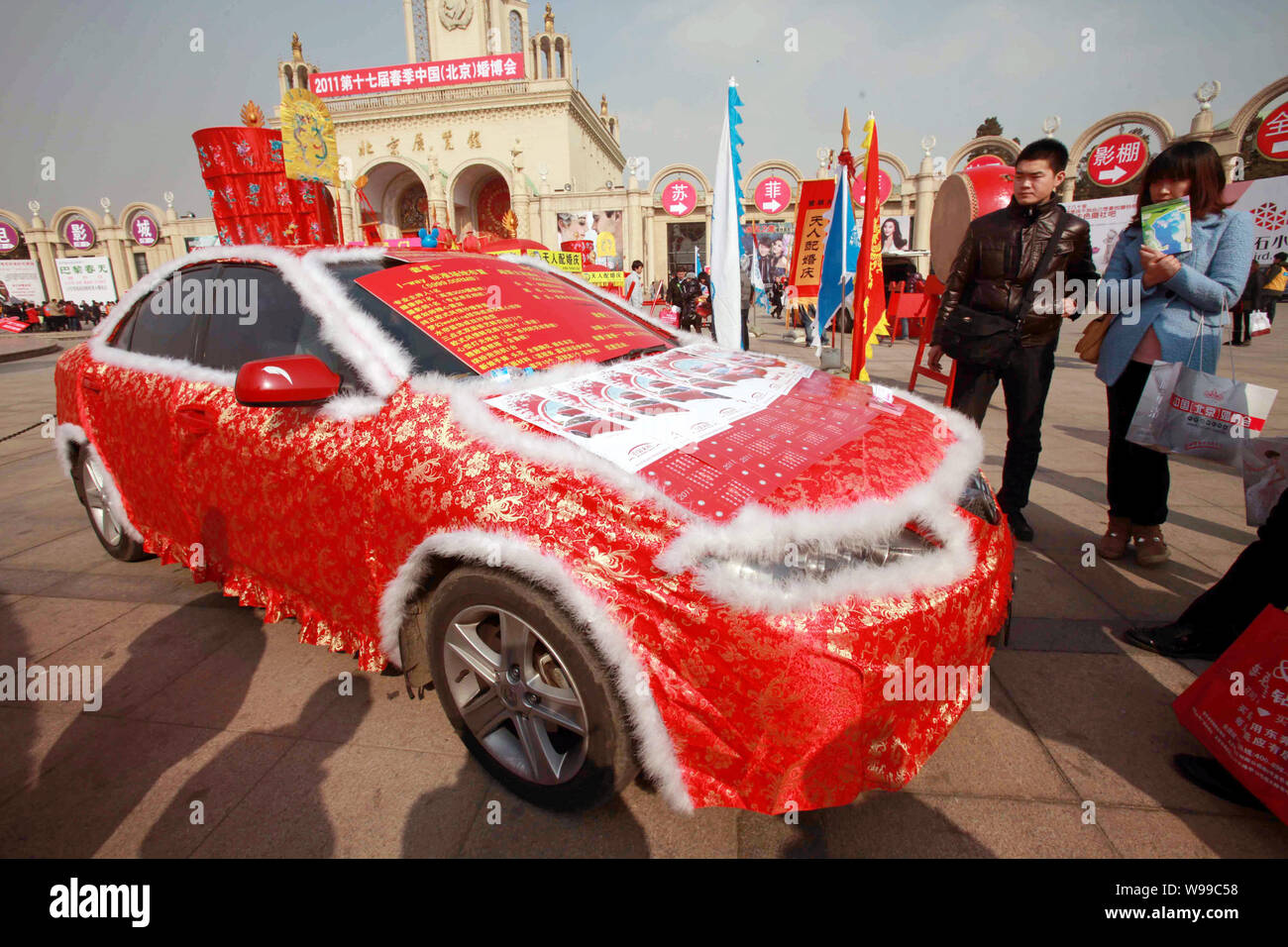 Visitors look at wedding cars dressed in materials traditionally used ...