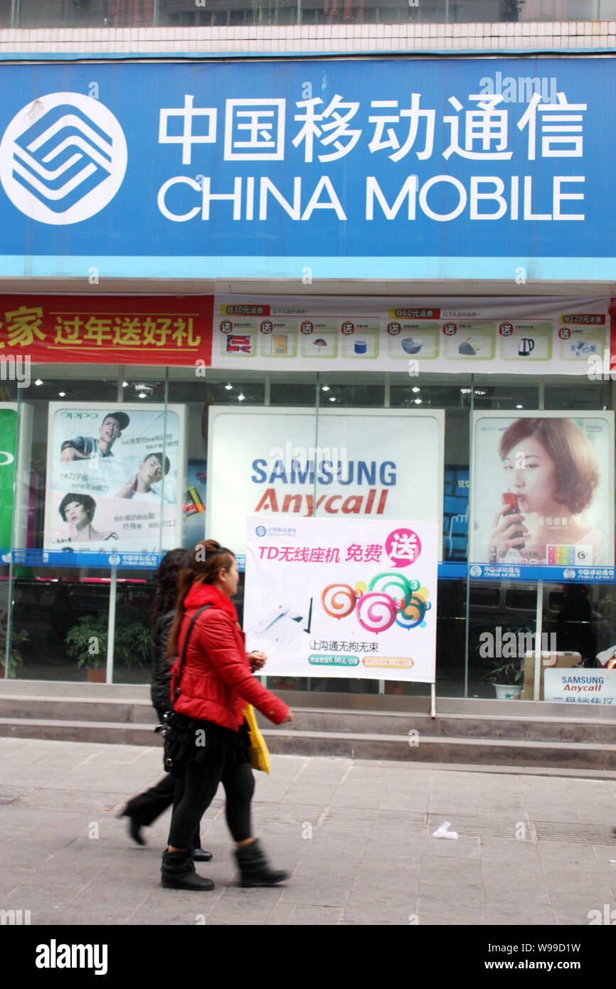 Two local residents walk past a branch of China Mobile in Yunyang ...